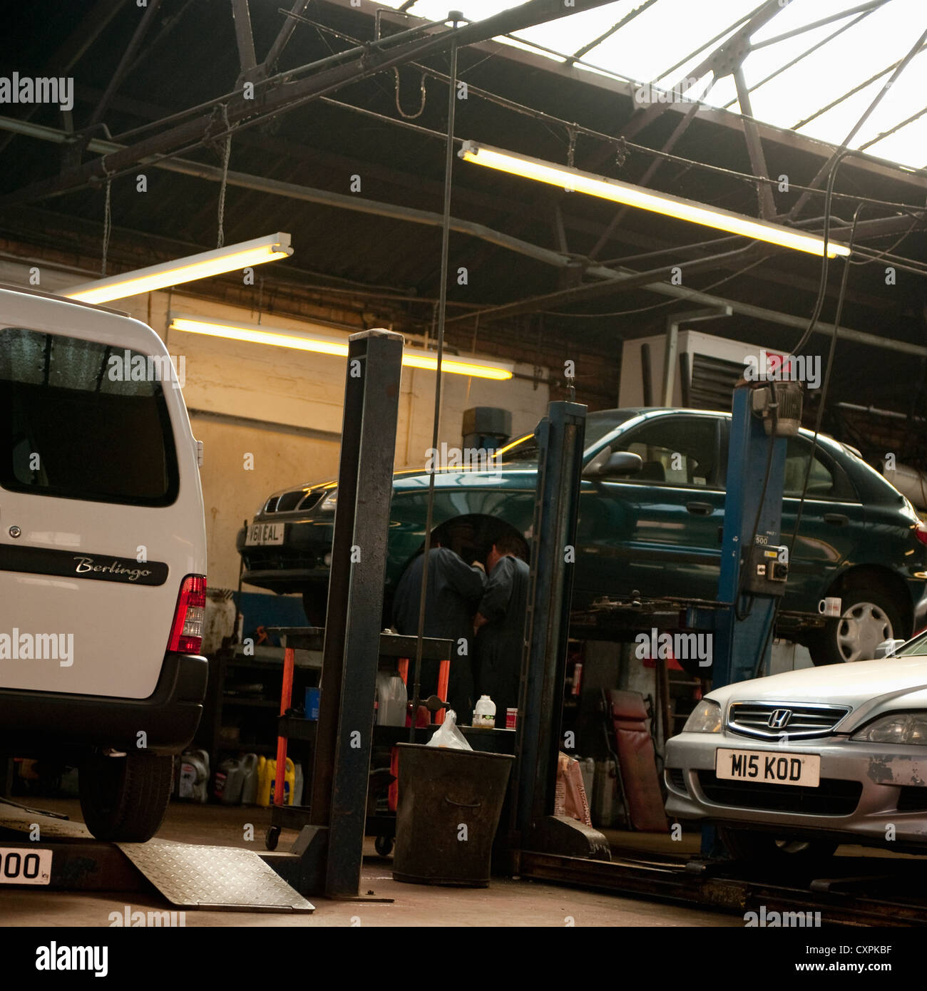 Two mechanics working on the wheel arch of a car on a ramp Stock Photo ...