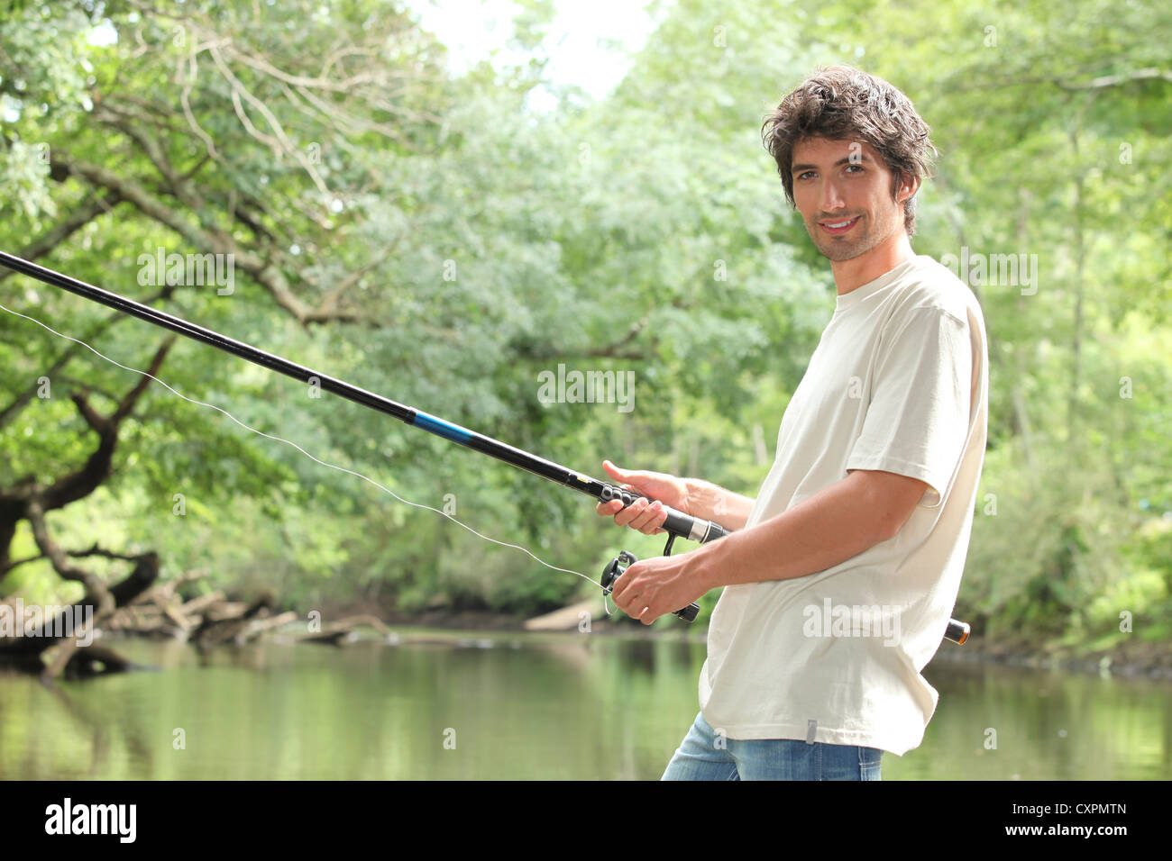 Man fishing by a river Stock Photo - Alamy