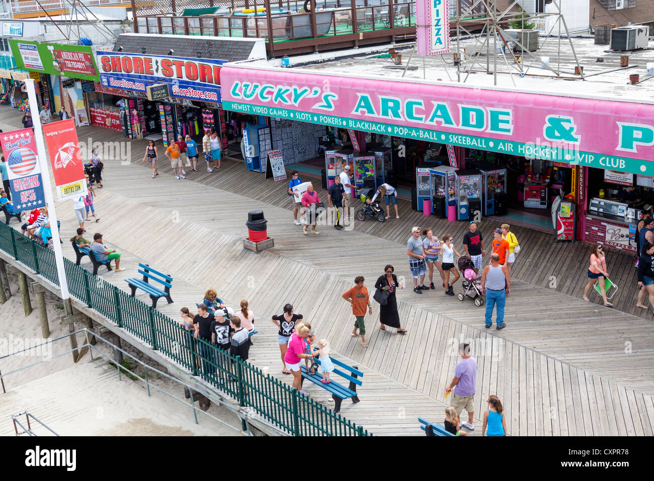 People walking on an ocean boardwalk surrounded by food, games and a ...