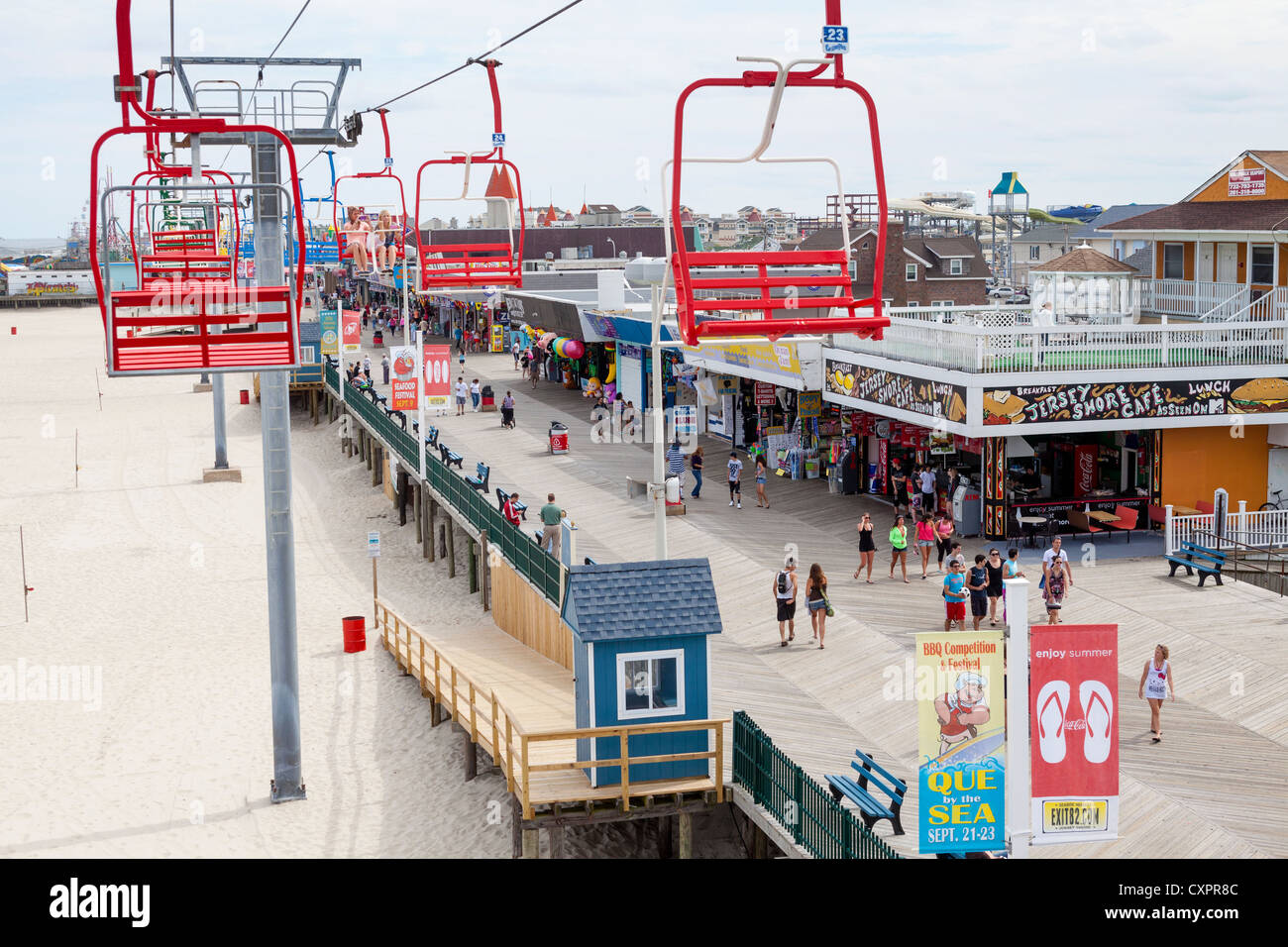 People walking on an ocean boardwalk surrounded by food, games and a ...