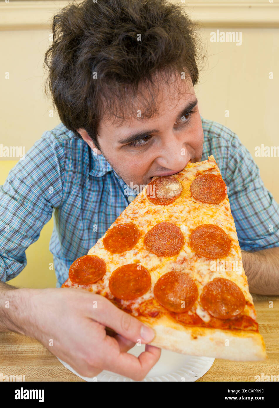 A young man eating a slice of pizza Stock Photo - Alamy