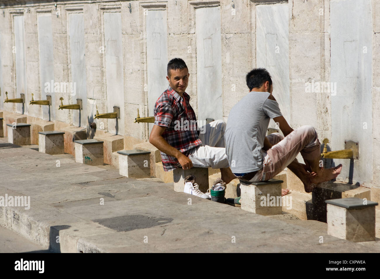 Two men washing their feet in the wudu (ablution) area outside a mosque ...