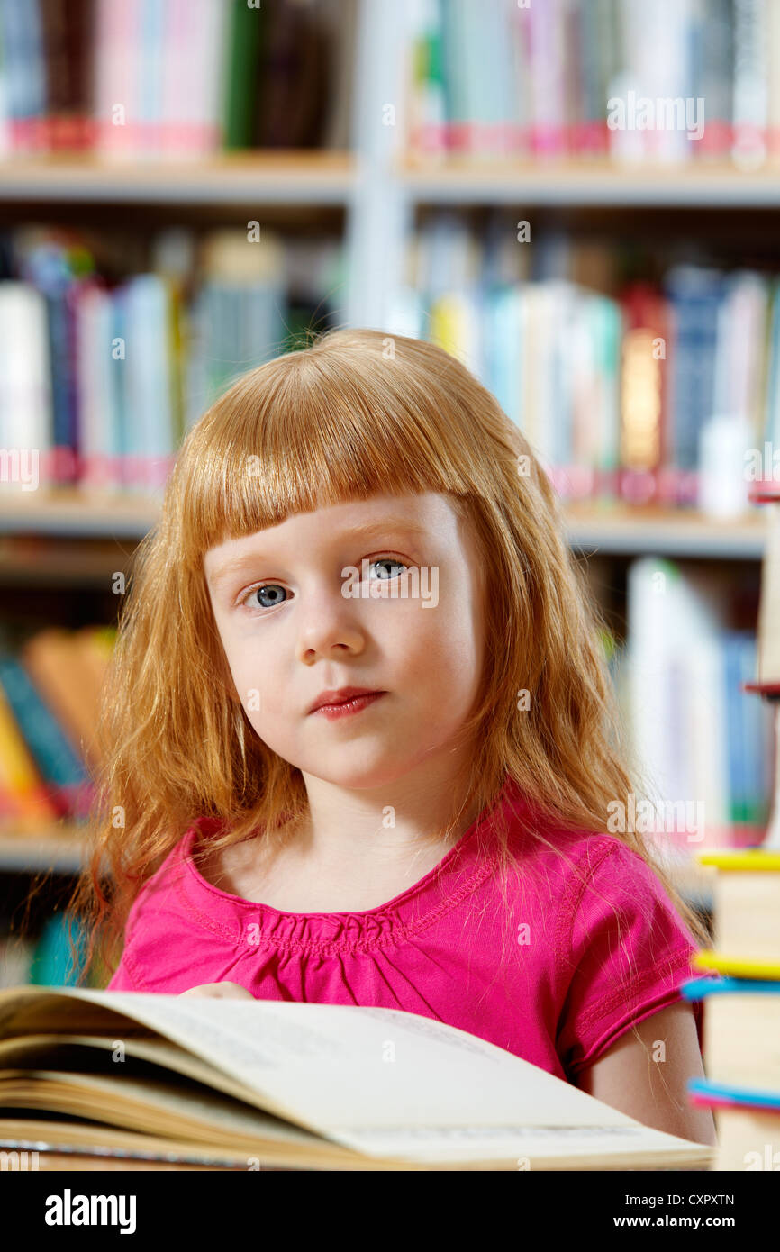 Portrait of smart girl reading book in library Stock Photo - Alamy