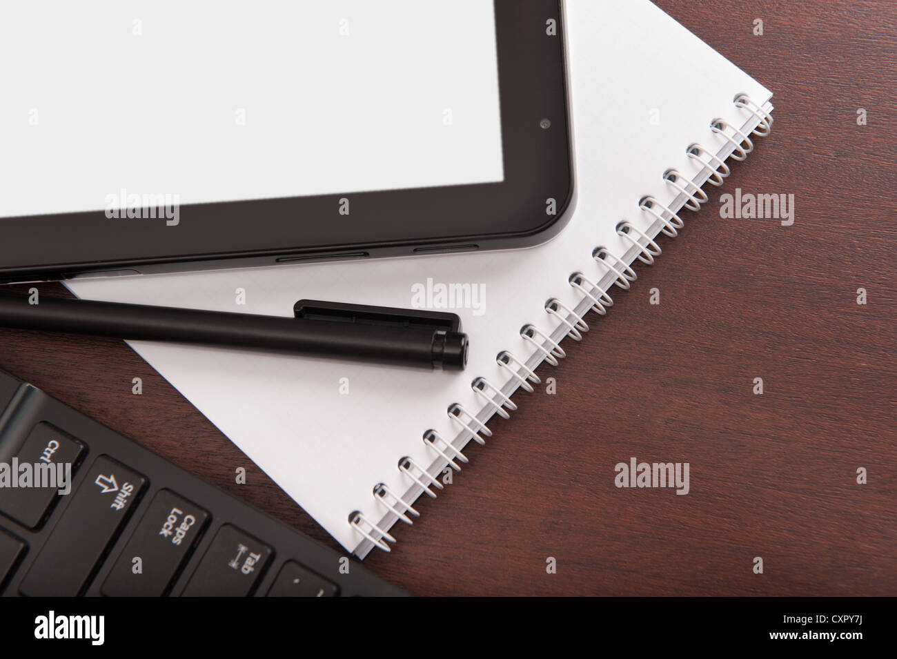 Tablet computer with white screen and laptop, pen and paper notebook ...