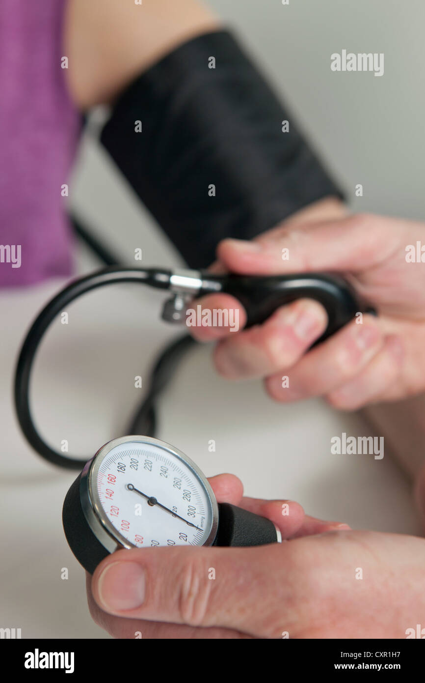 Doctor using blood pressure gauge on patient during medical examination ...