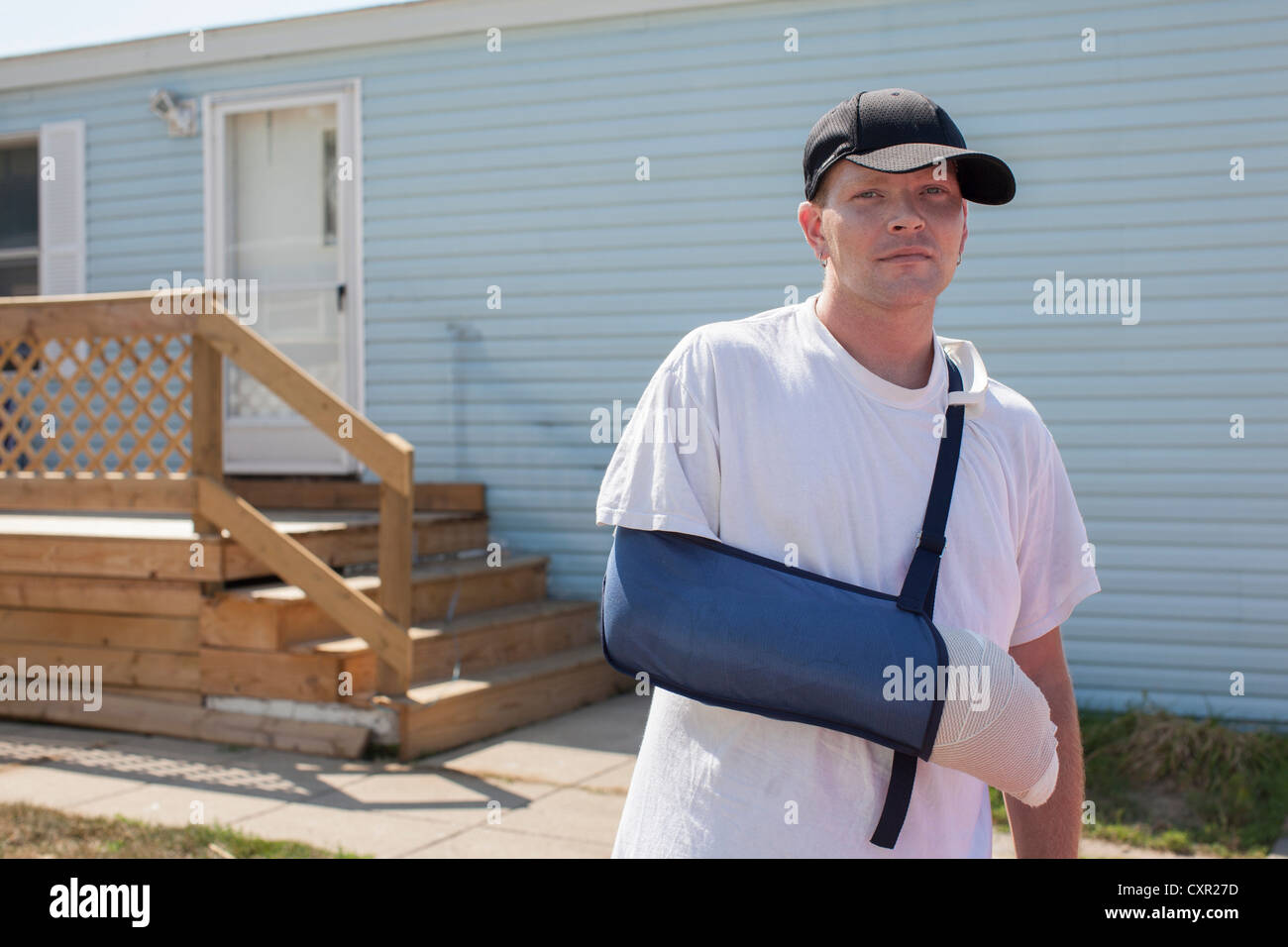 Man outside house with arm in sling Stock Photo - Alamy