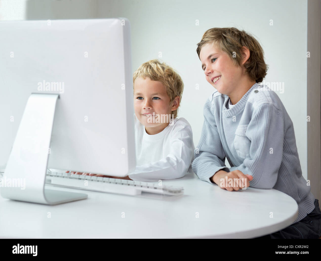 Brothers looking at computer screen Stock Photo - Alamy