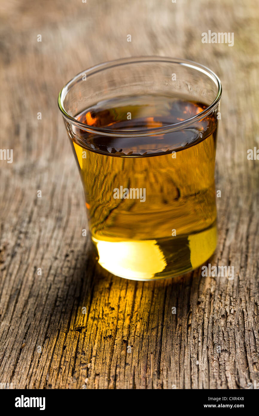 glass of golden alcohol on wooden table Stock Photo - Alamy