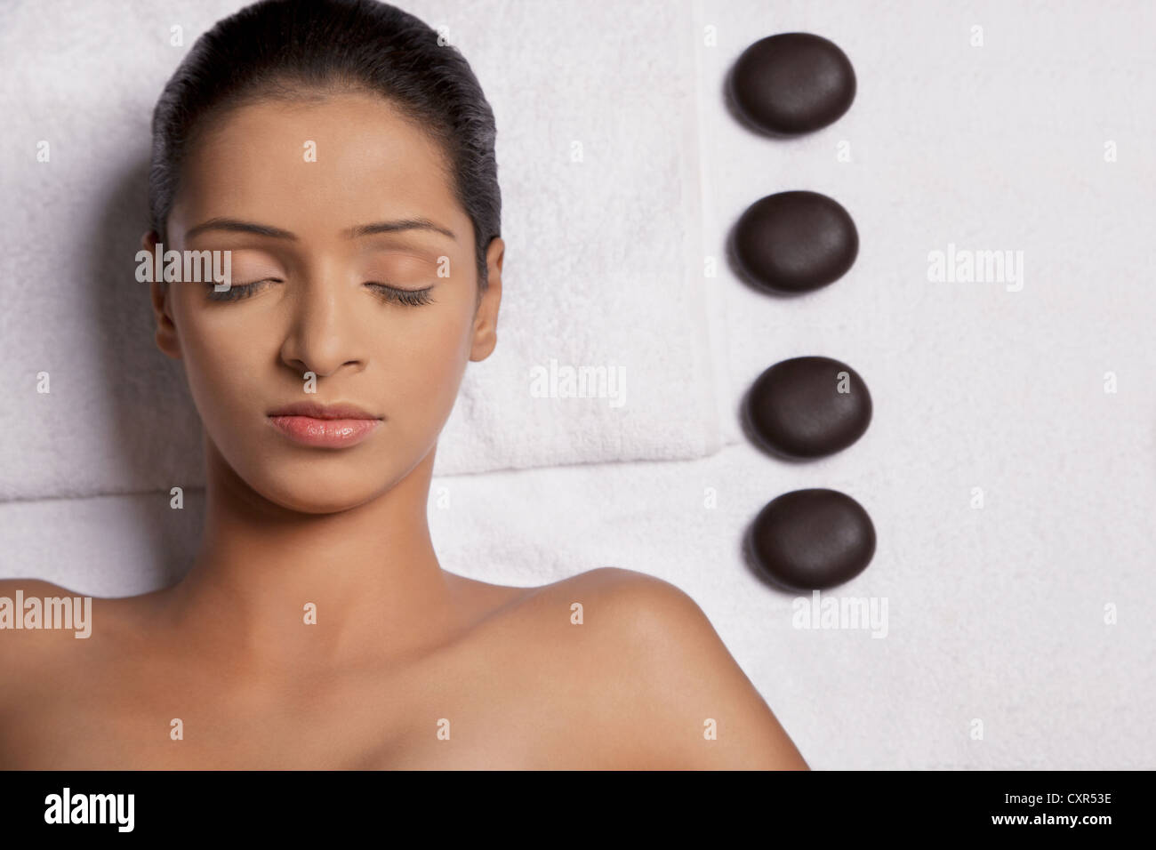 Woman lying on massage table with pebble stones on side Stock Photo - Alamy