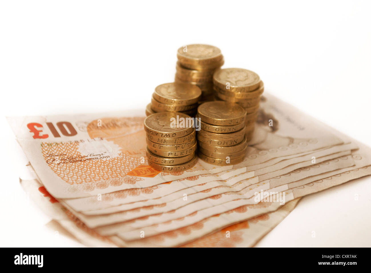 One pound coins stacked on ten pound notes, currency, money on white ...