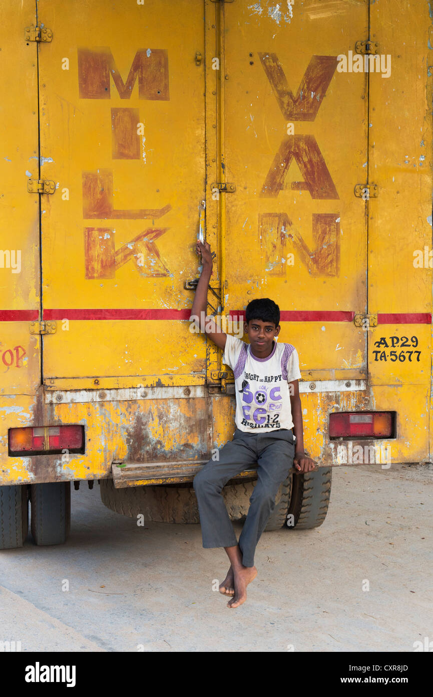 Indian boy hitching a ride on the back of a milk van. Andhra Pradesh ...