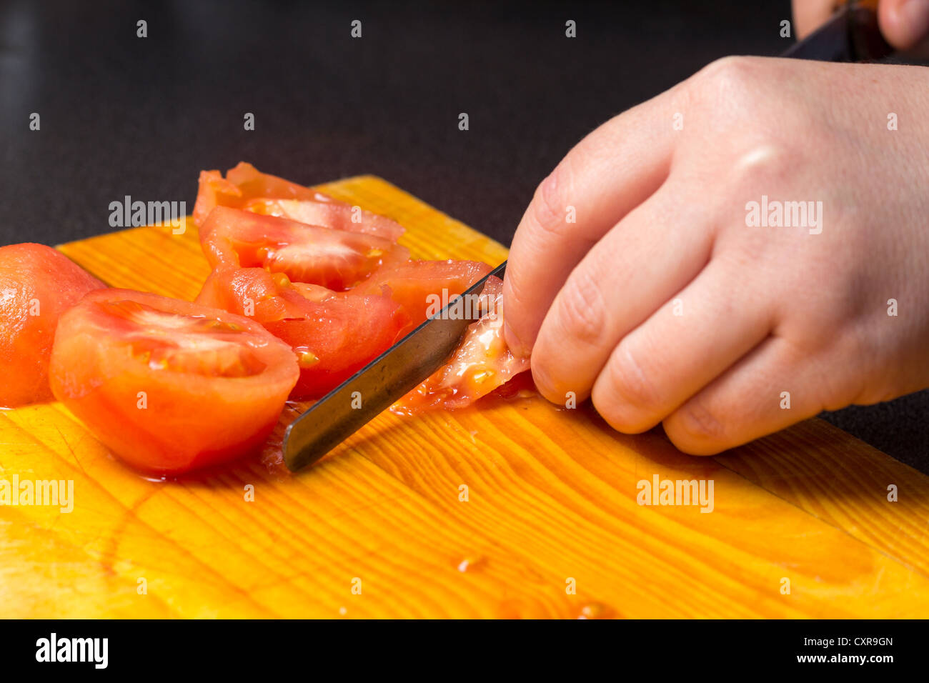 Woman's hand slicing tomatoes on a wood cutting board Stock Photo - Alamy
