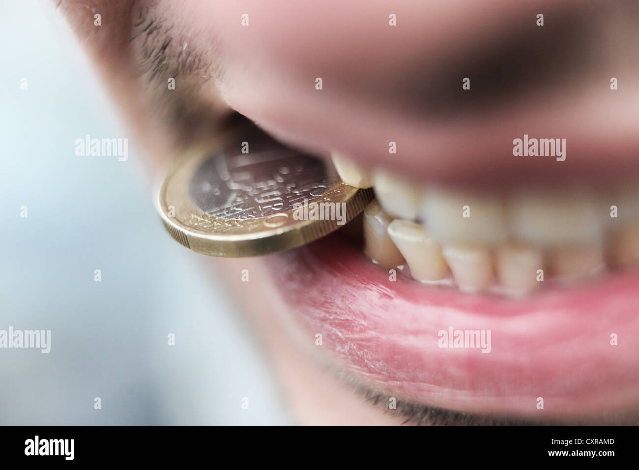 Man with an euro coin between his teeth, symbolic image for euro crisis ...