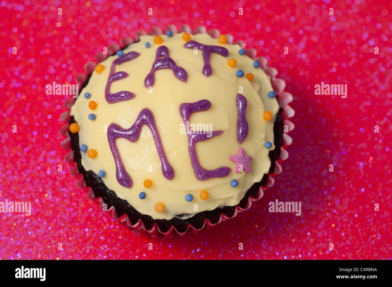 Cake with the words Eat Me iced onto it on a pink sparkly background ...