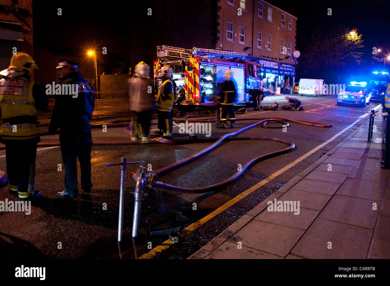 Firefighters at night hose hydrant building on fire Stock Photo - Alamy
