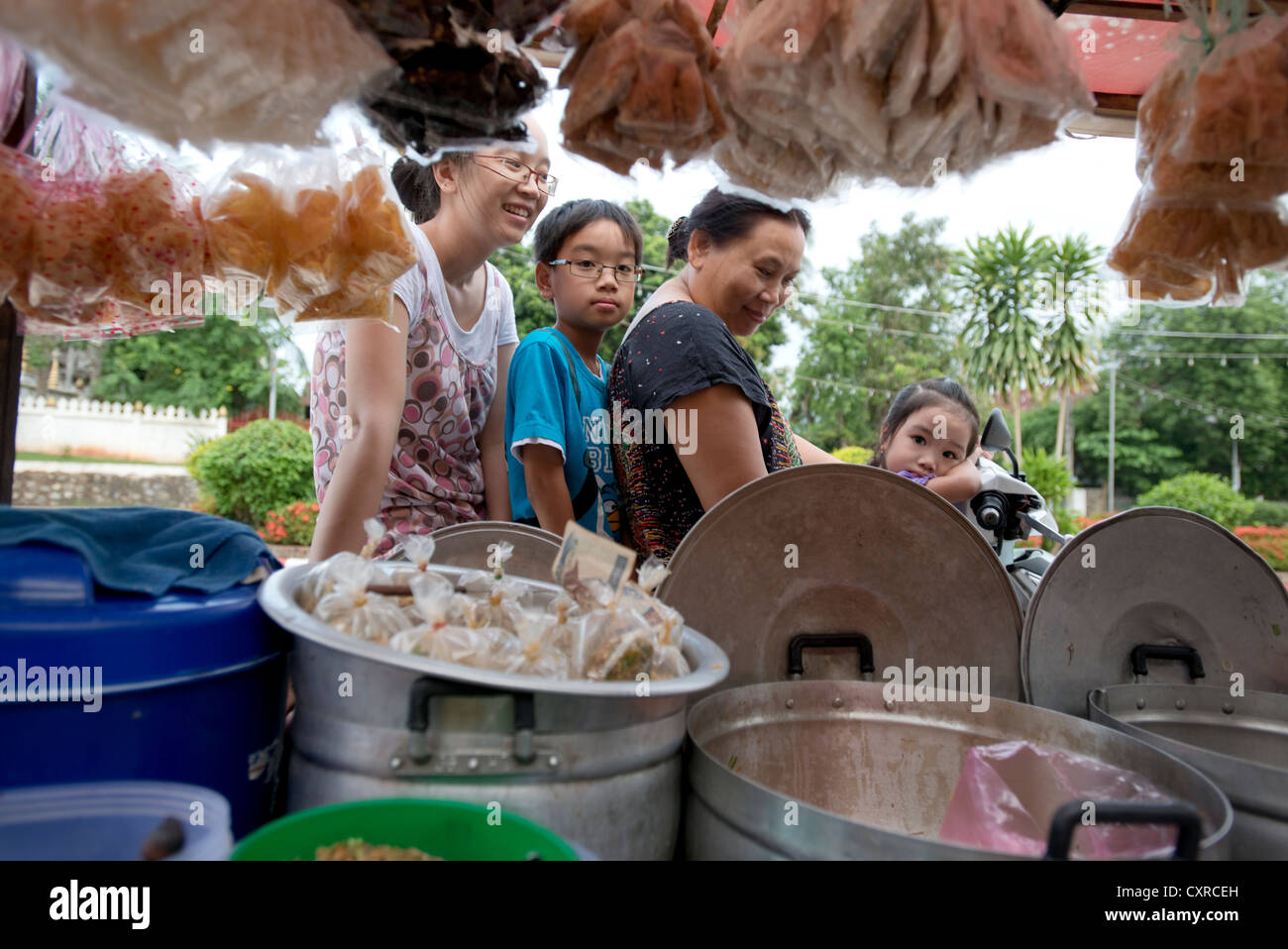 A family stop by a food stall for a takeaway in Luang Prabang, Laos ...