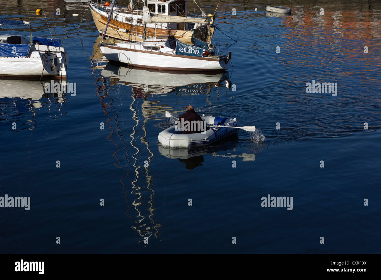 Man rowing an inflatable dinghy in Port Seton harbour, East Lothian ...