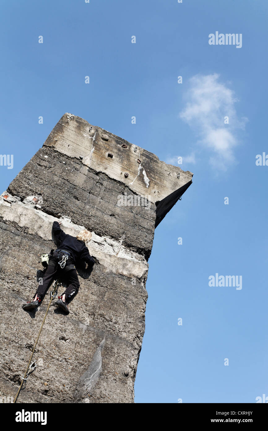 Boy climbing a high concrete pillar, climbing wall at a former ore ...