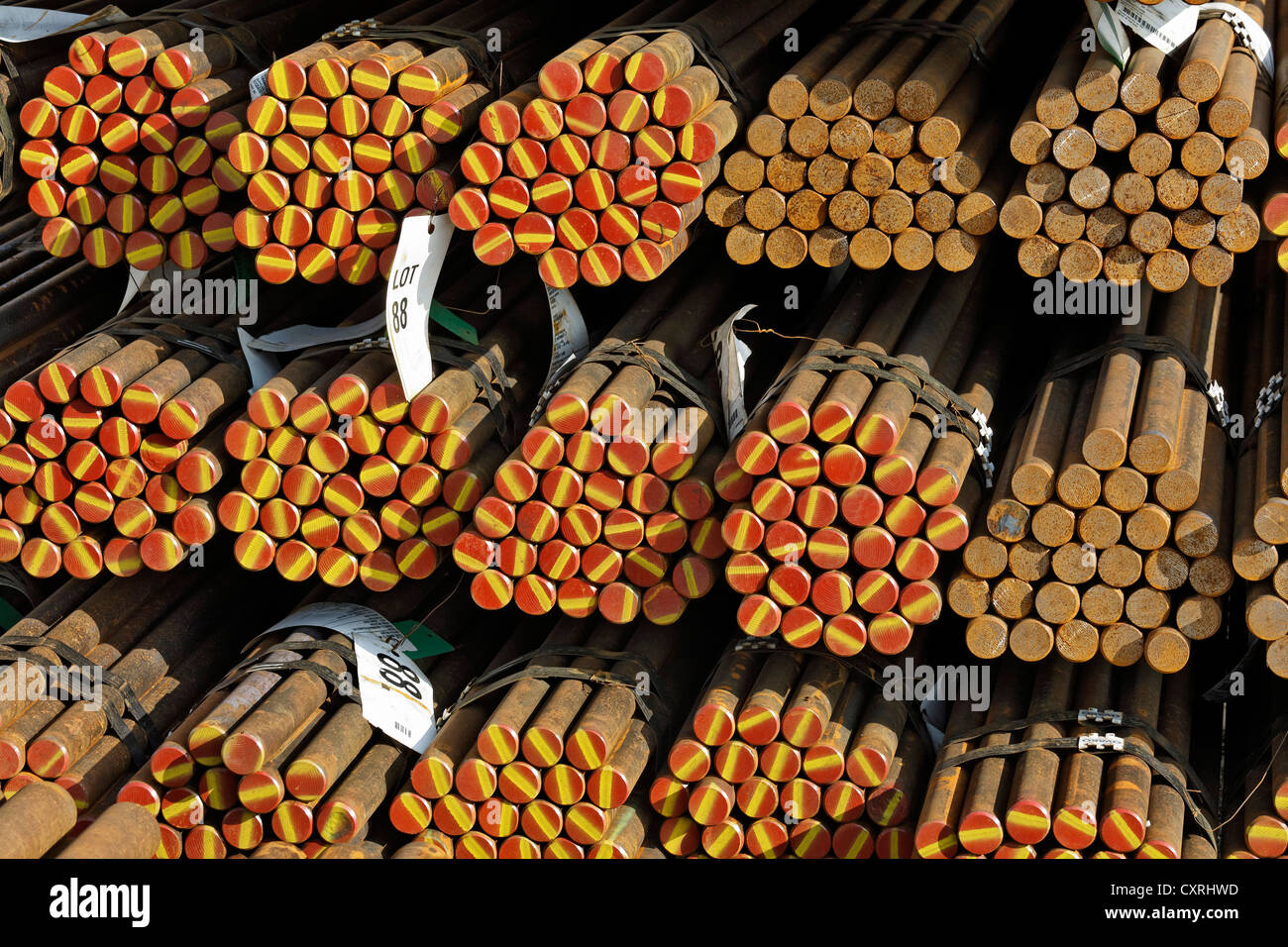 Round steel bars with coloured markings, storage yard of a steel trader ...