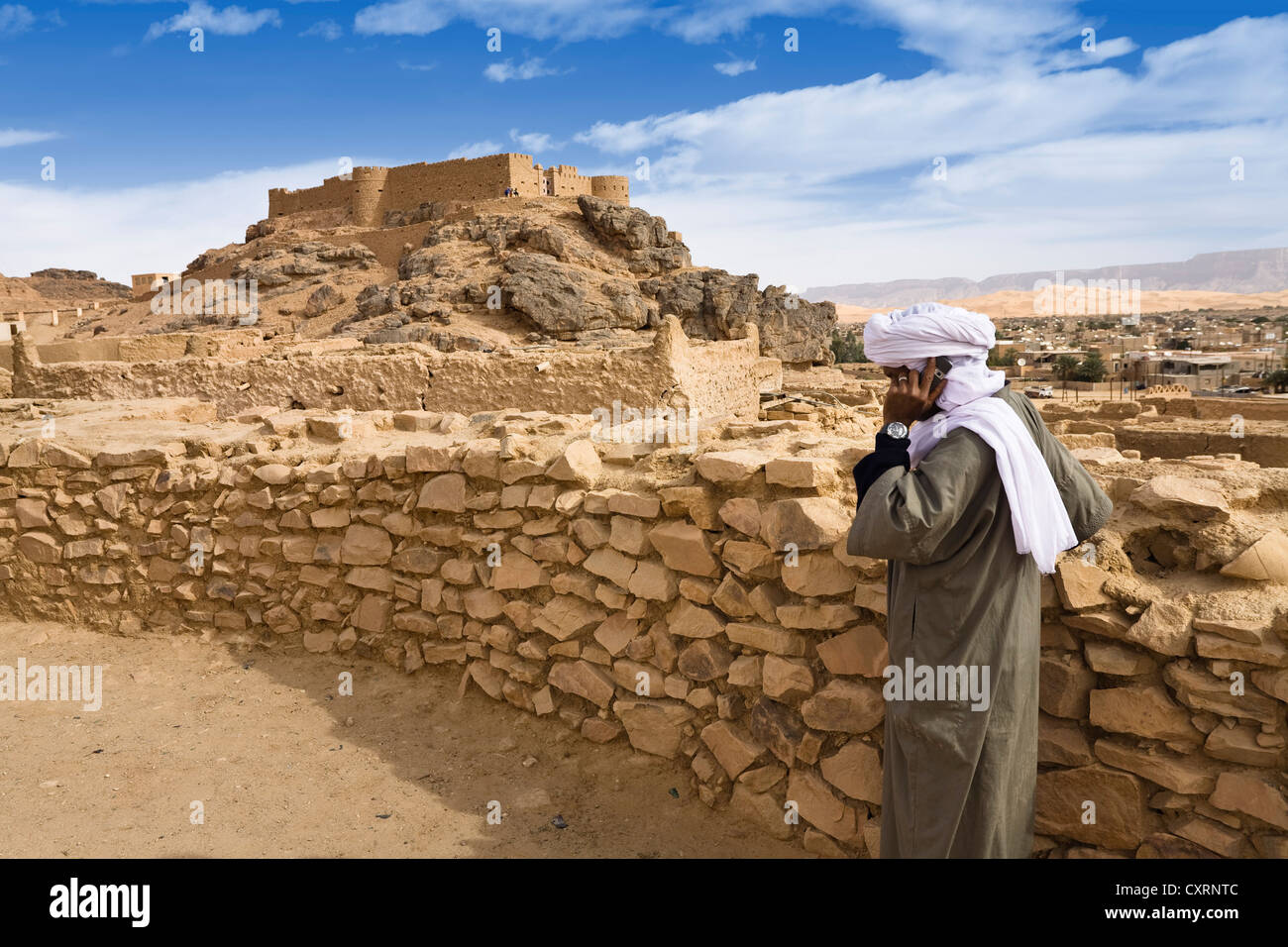 Bedouin man with a mobile phone in the old town of Ghat with Fort ...