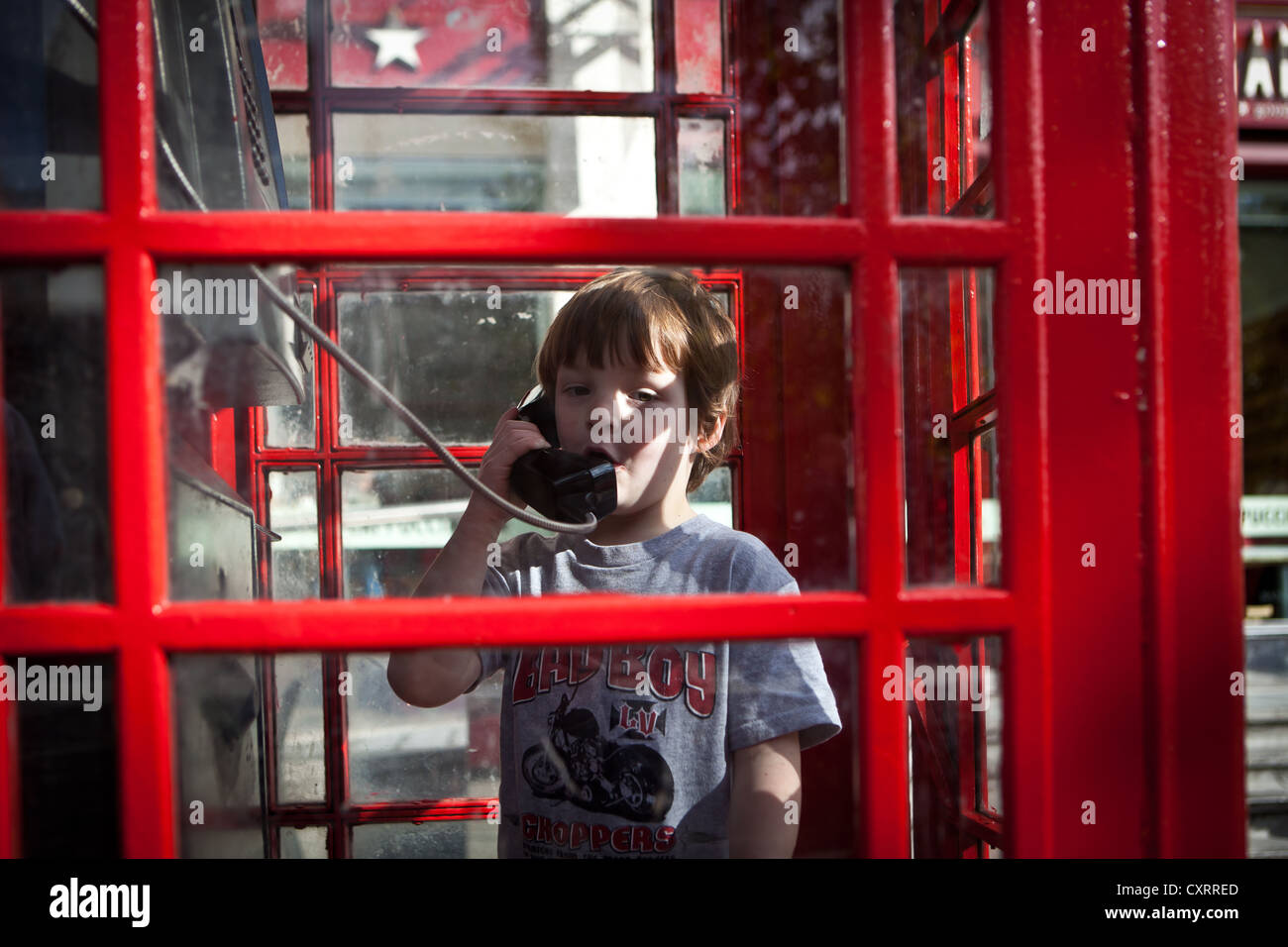 Young boy making phone call from red telephone box Stock Photo - Alamy