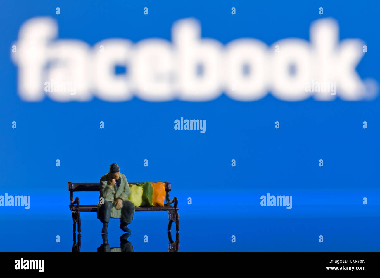 Homeless man sitting on a bench, miniature figure in front of a blurred ...