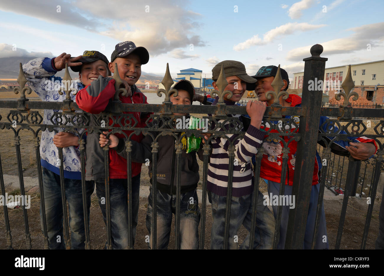 Mongolian boys with baseball caps standing behind a fence of a school ...