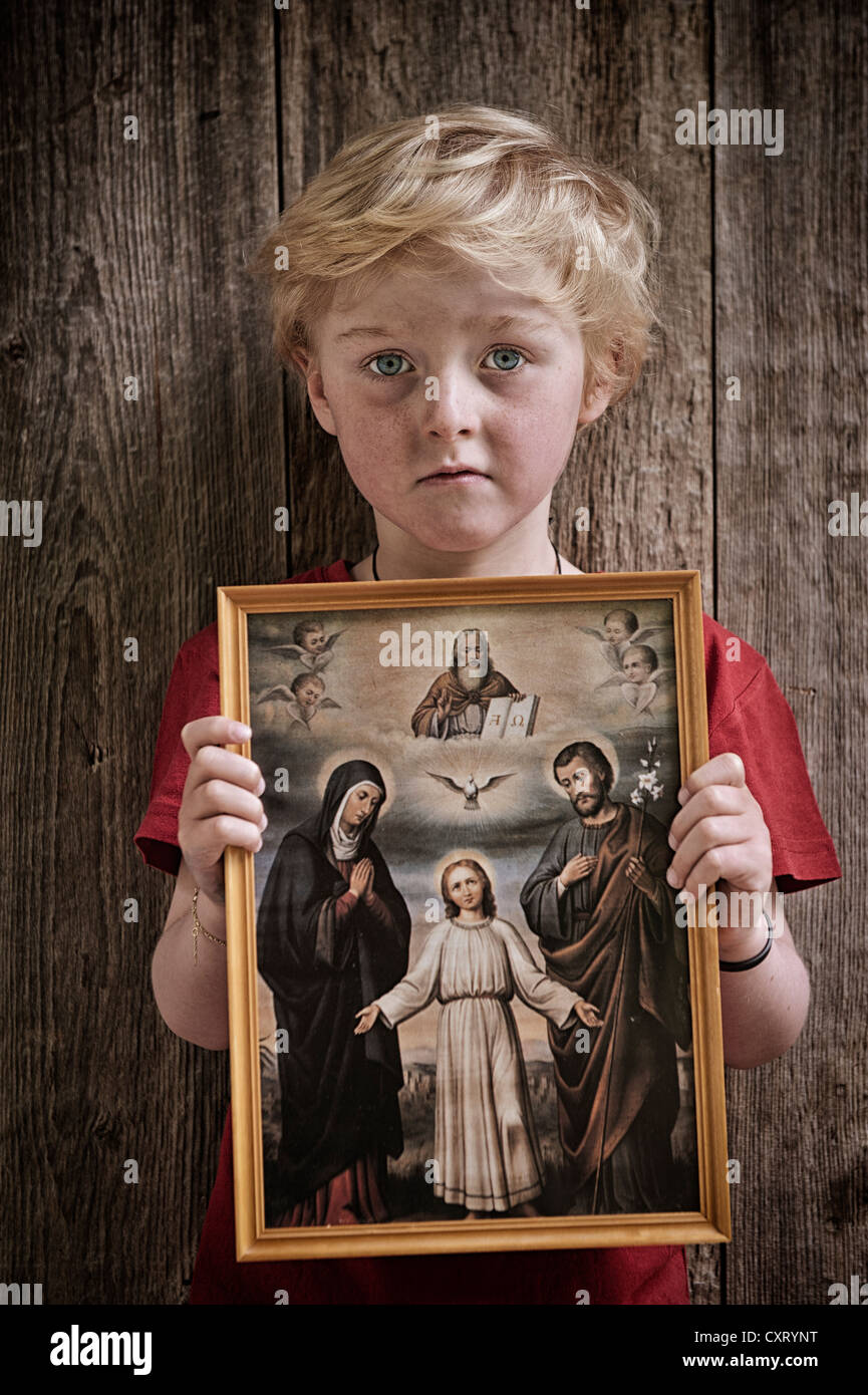 Boy holding a Christian image of saints, with Jesus, Mary and Joseph ...