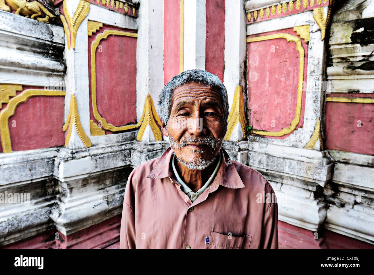 Old man standing in front of the walls of a monastery, Burma, Myanmar ...