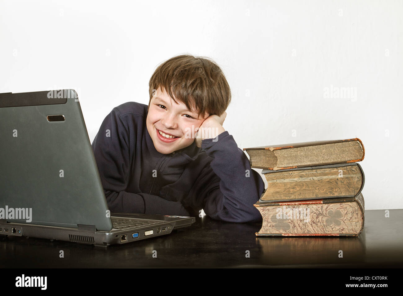 Boy with a laptop and a stack of books Stock Photo - Alamy