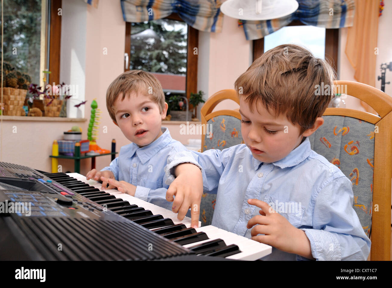 Twin boys, 4, playing music together on a keyboard Stock Photo - Alamy
