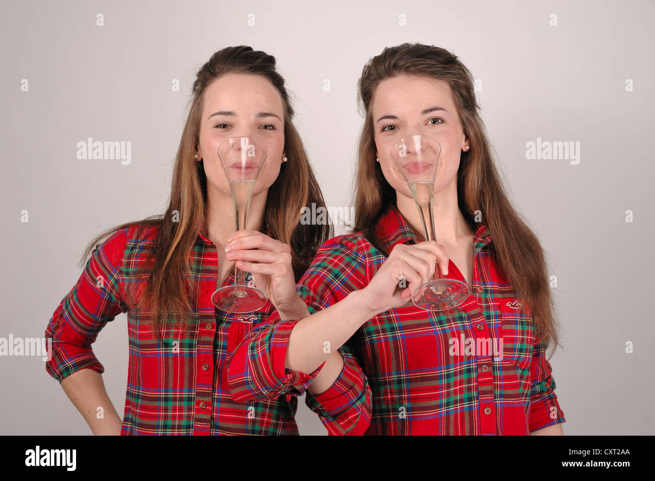 Twin sisters drinking to brotherhood from champagne glasses Stock Photo ...