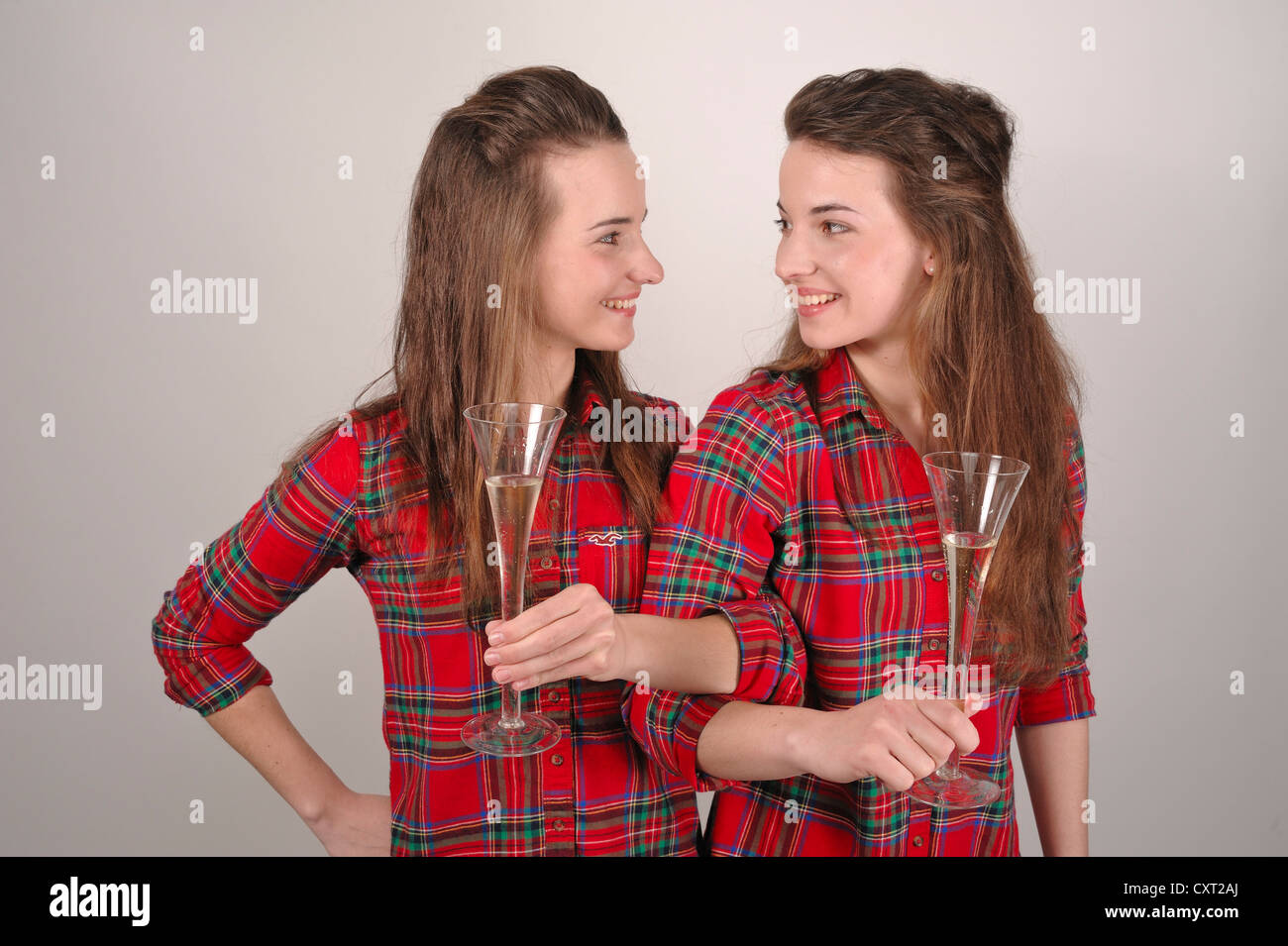 Twin sisters drinking to brotherhood from champagne glasses Stock Photo ...