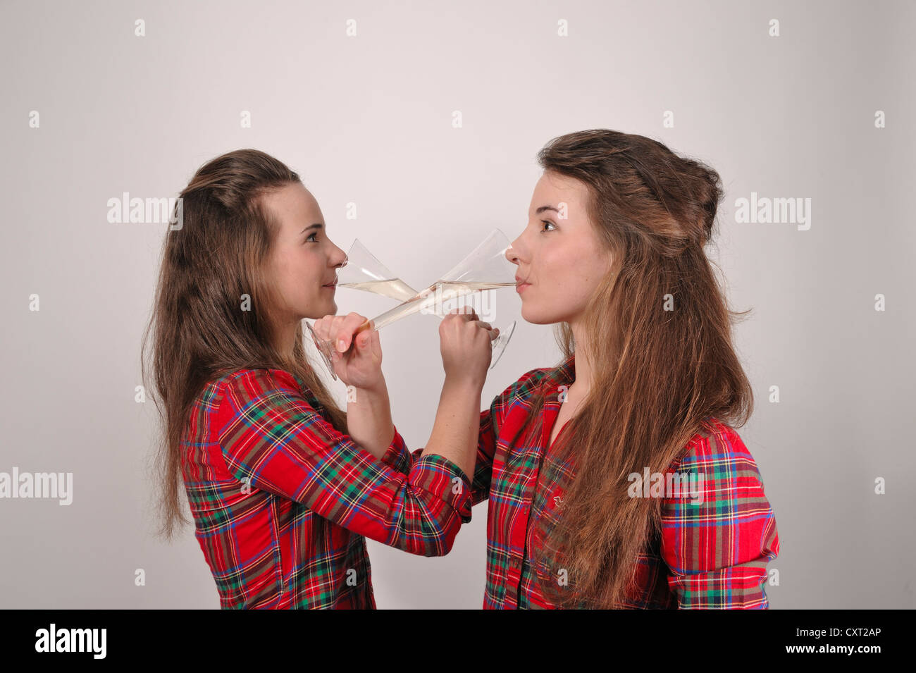 Twin sisters drinking to brotherhood from champagne glasses Stock Photo ...