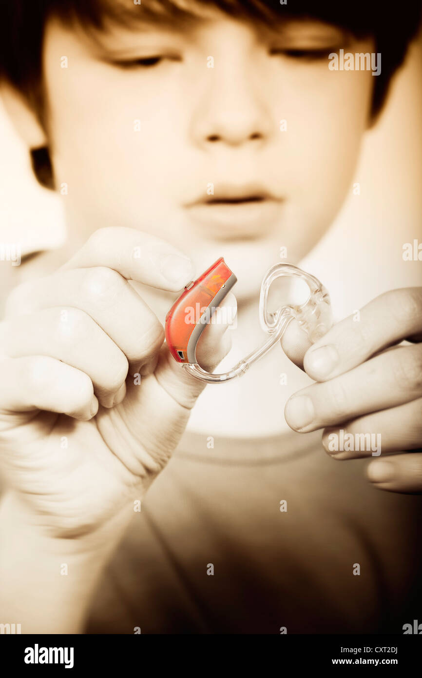 Boy looking at a hearing aid device Stock Photo - Alamy