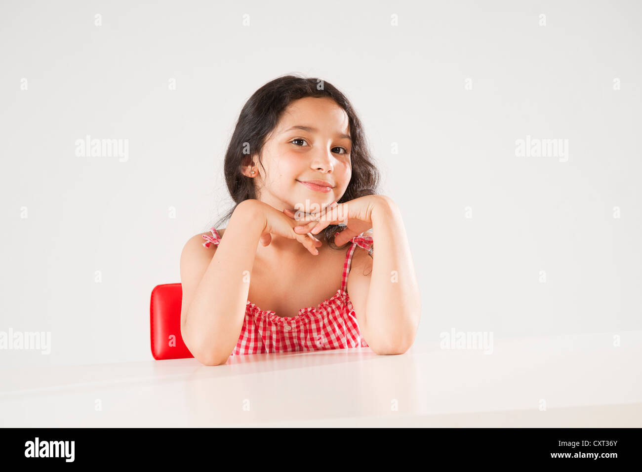Girl sitting at a table Stock Photo - Alamy