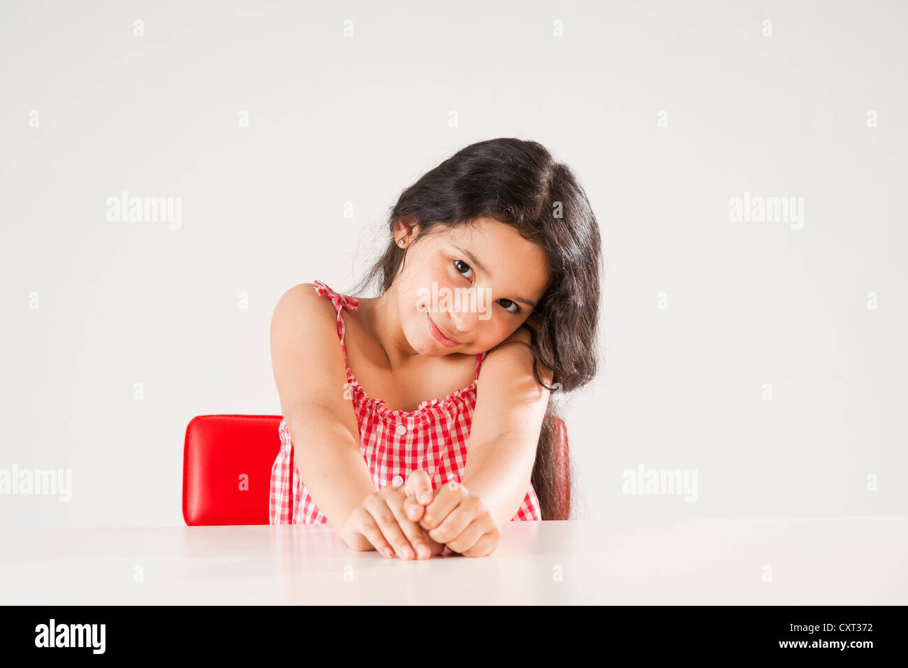 Girl sitting at a table Stock Photo - Alamy