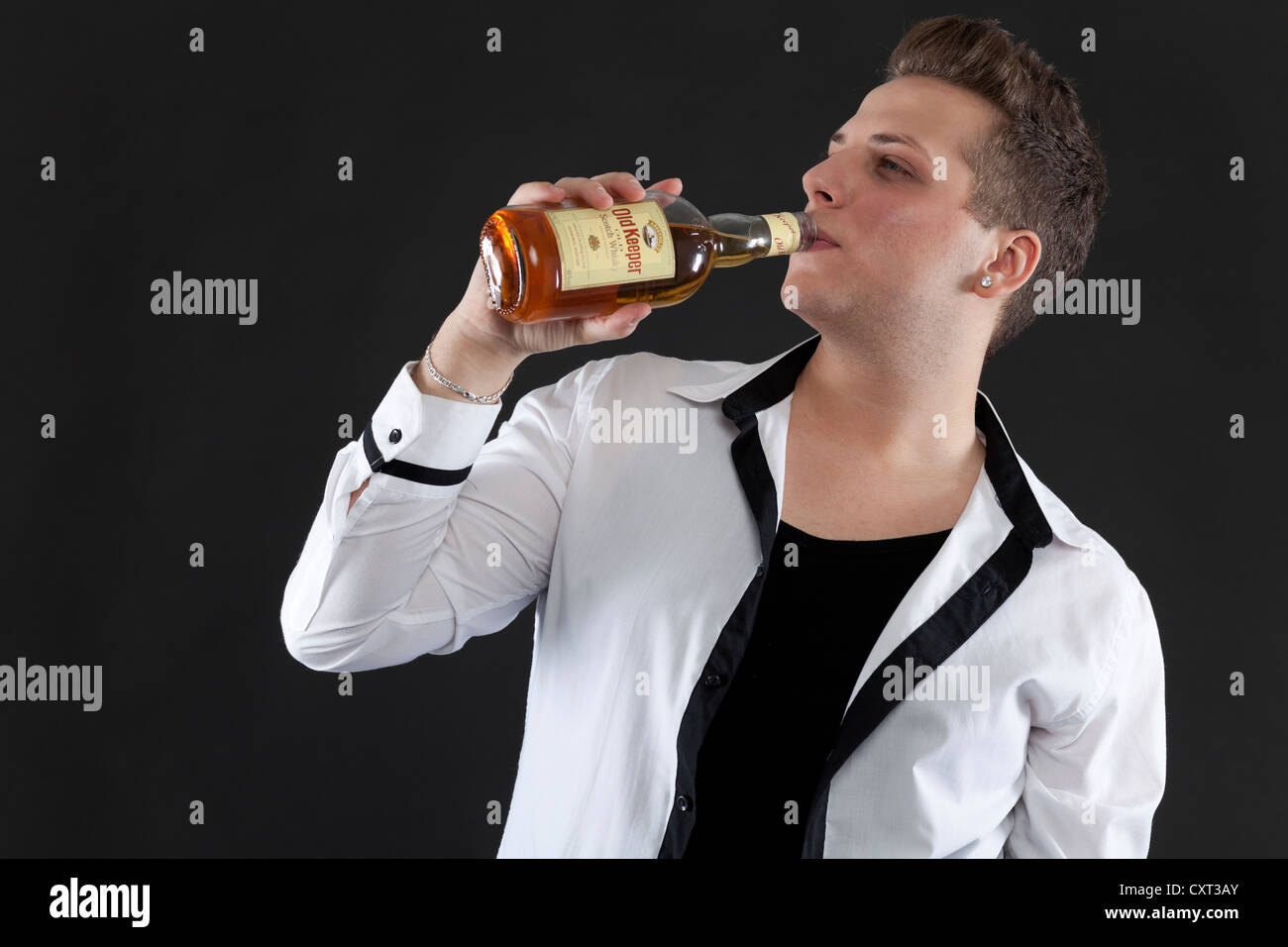 Young man holding a bottle of whiskey Stock Photo - Alamy