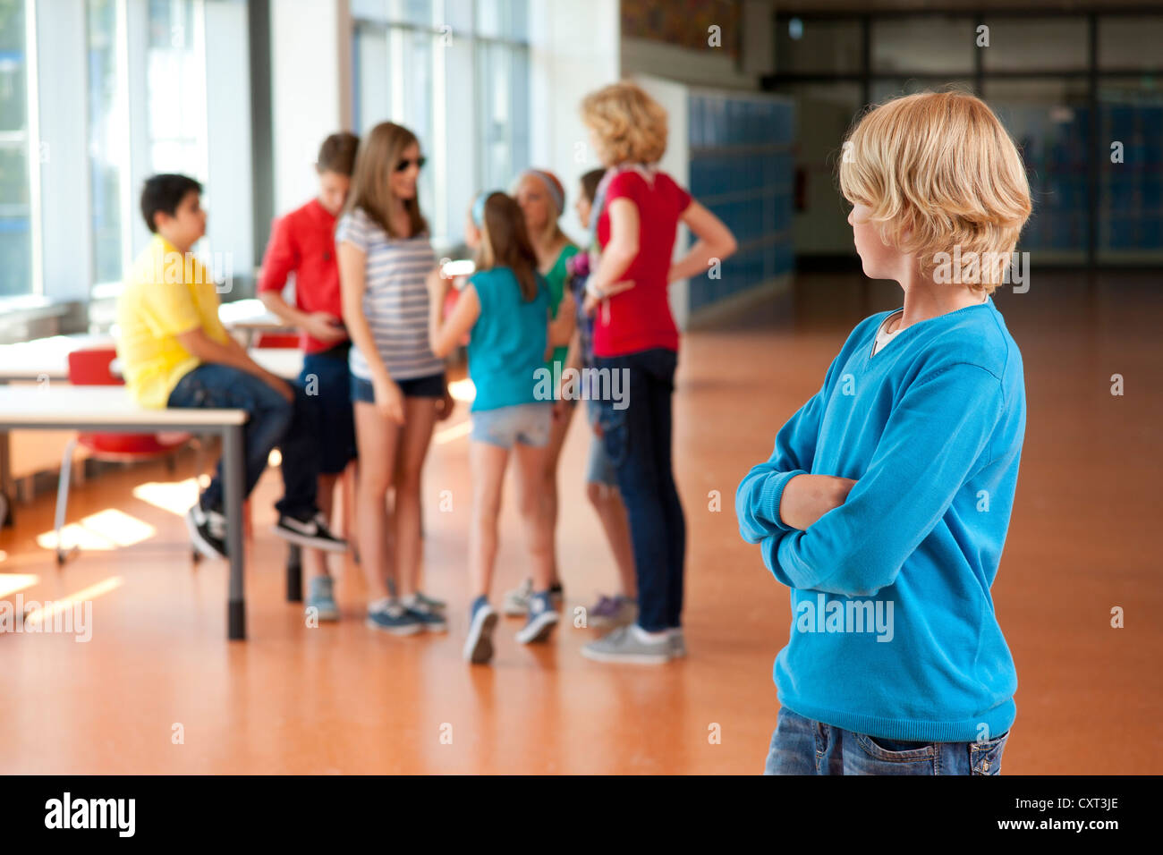 Schoolchildren in a school building, one boy looking sad and standing ...