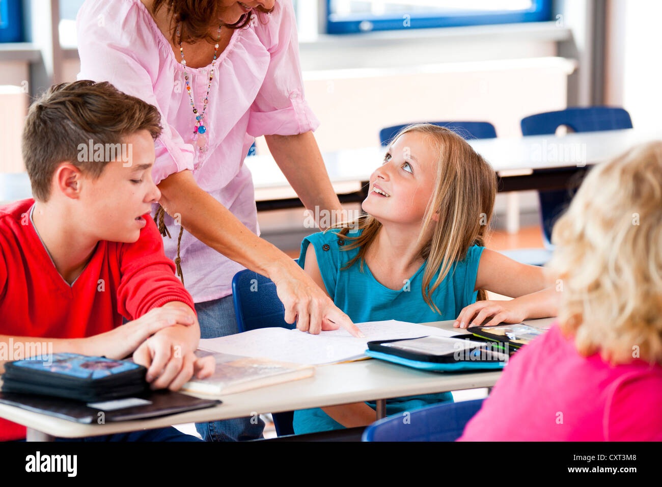 Teacher helping schoolchildren with a task Stock Photo - Alamy
