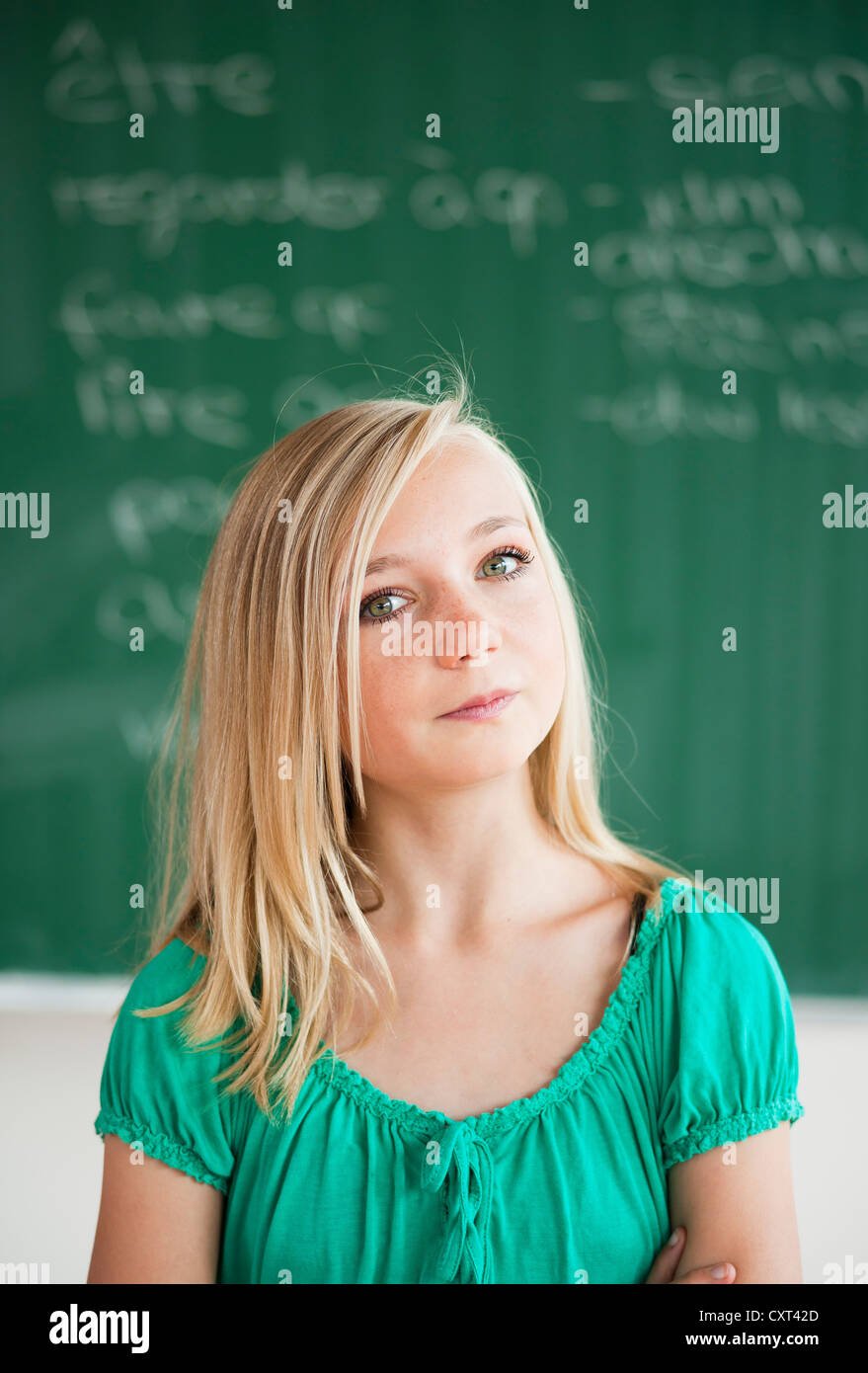 Schoolgirl standing in front of a blackboard in a classroom, portrait ...