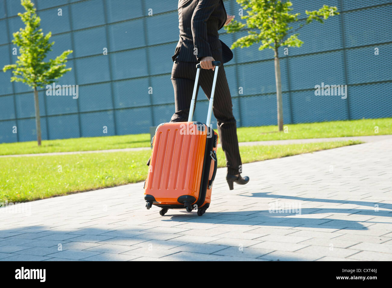 Businesswoman pulling a trolley suitcase behind her Stock Photo - Alamy