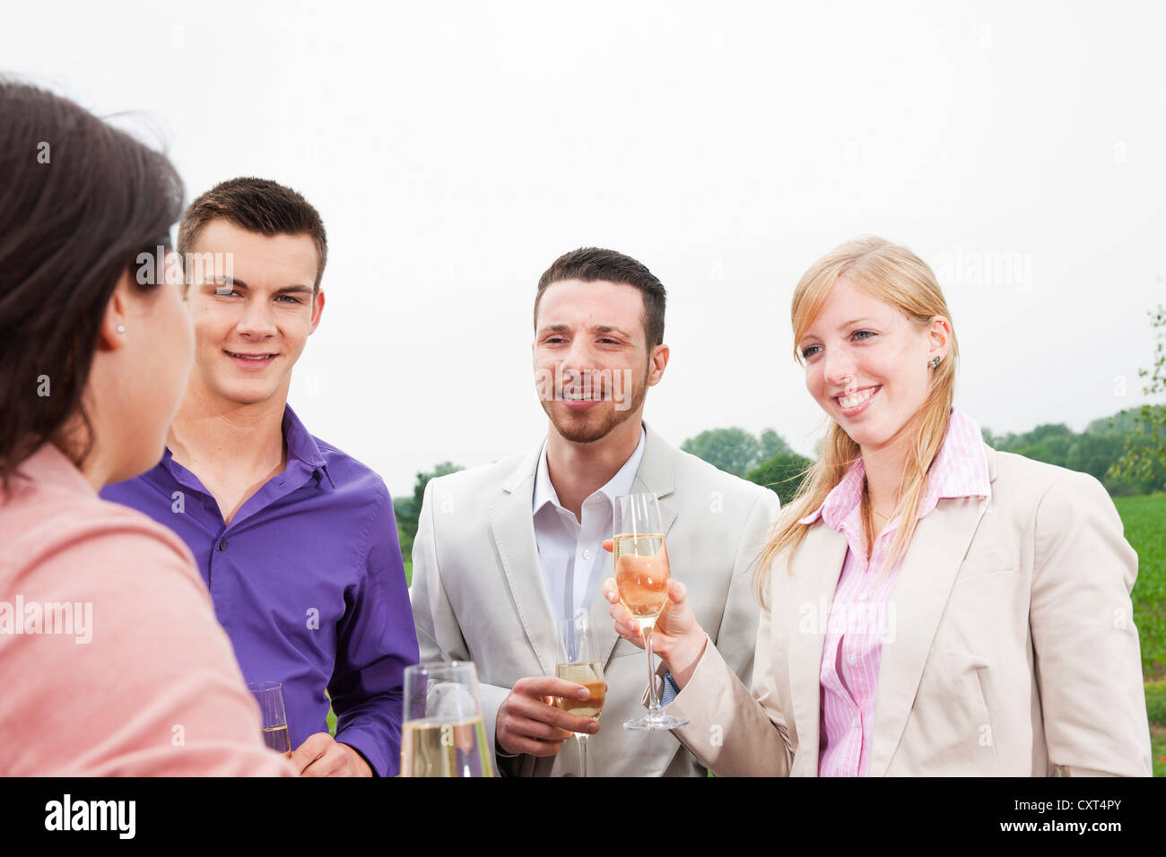 A group of young people chinking glasses, celebrating on a terrace ...