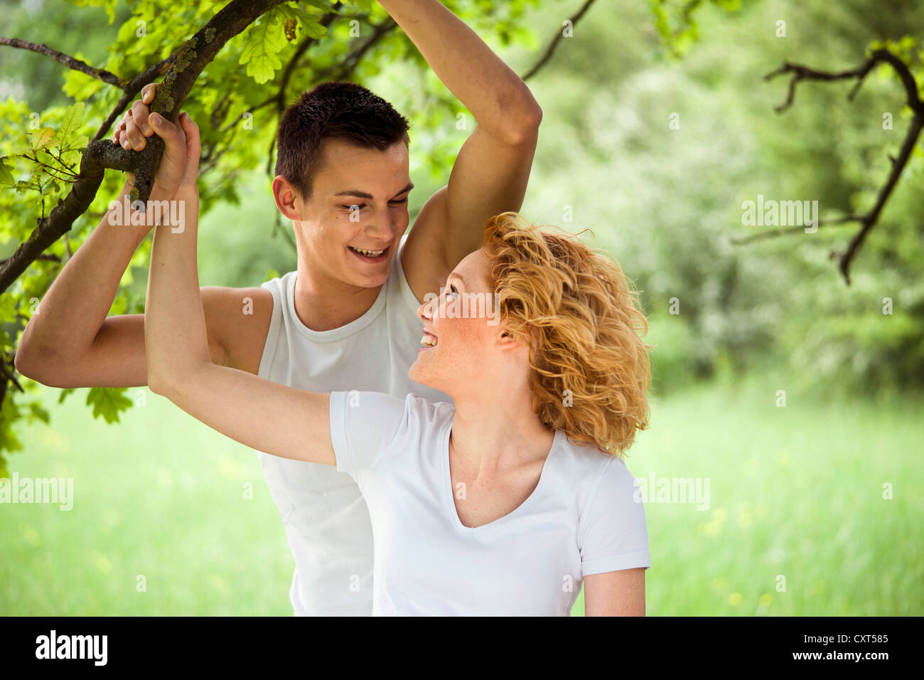 Happy young couple standing under a tree Stock Photo - Alamy