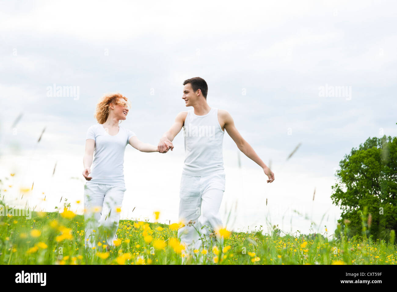 Young couple strolling happily through a floral meadow Stock Photo - Alamy
