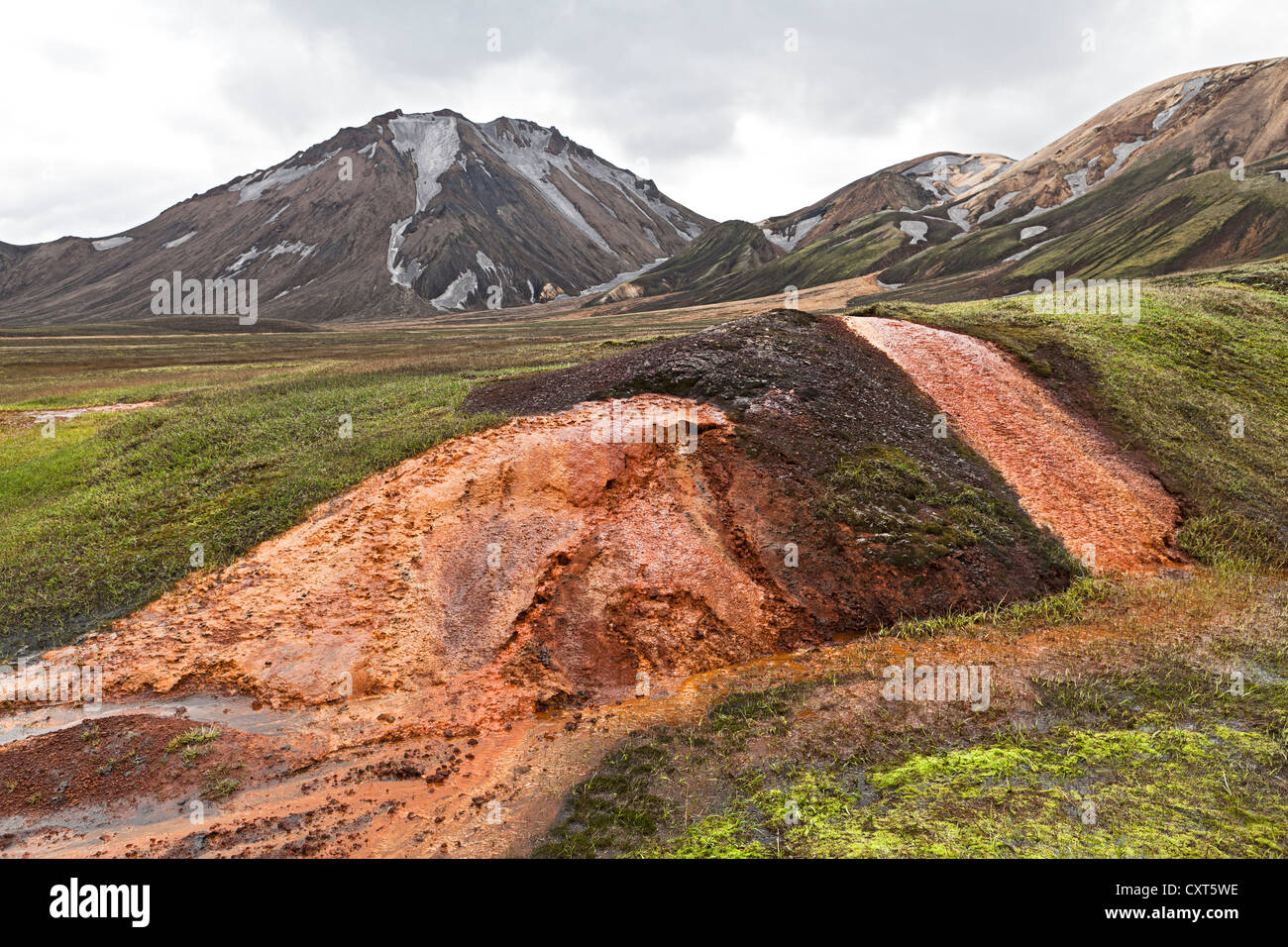 Water containing iron flowing down a hillside, staining the ground red ...