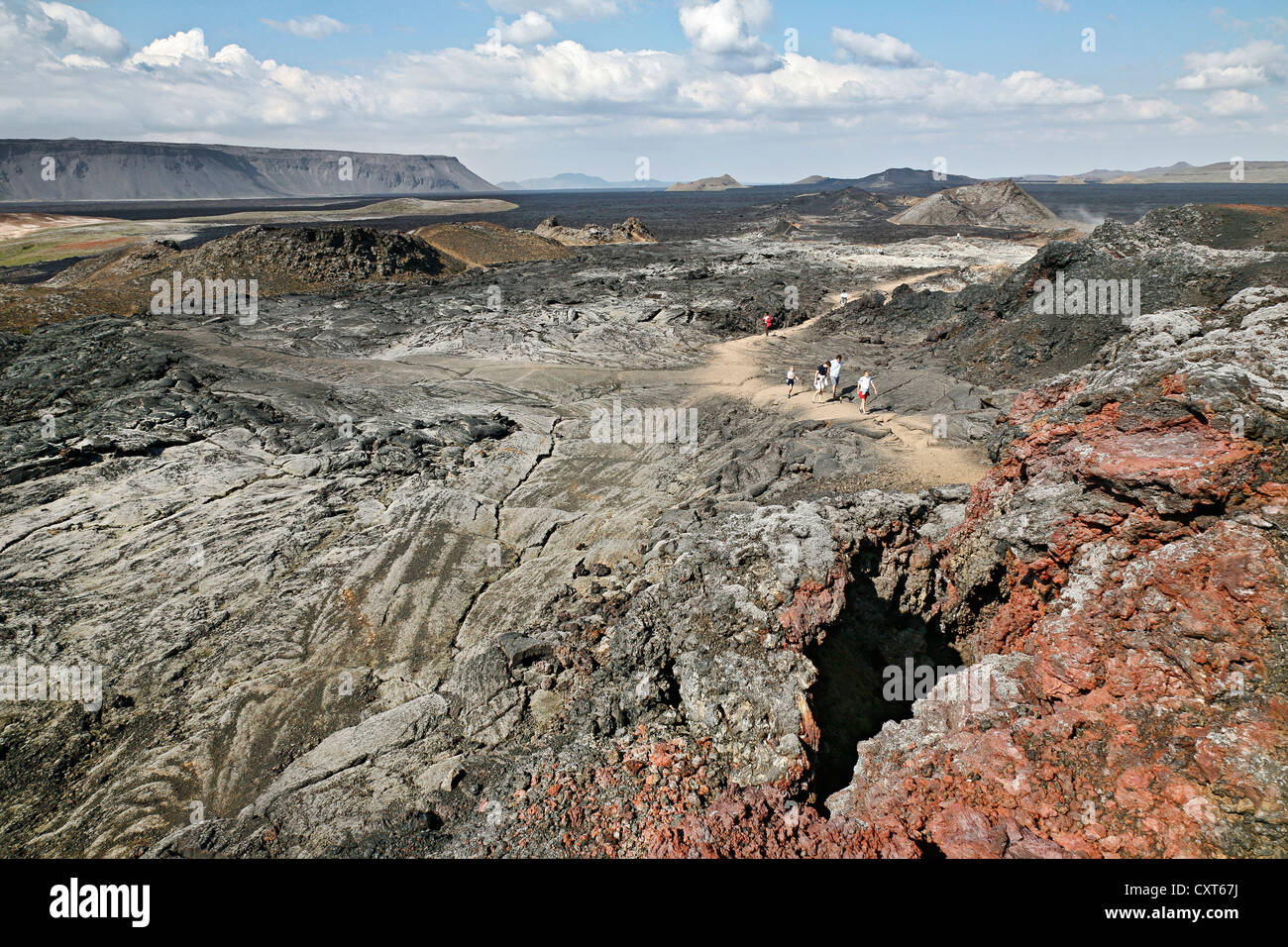 Visitors walking on a path in a landscape of lava fields, extinct ...