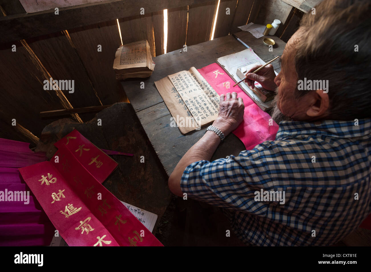 Elderly Chinese man sitting at a desk, ethnic minority, practicing ...