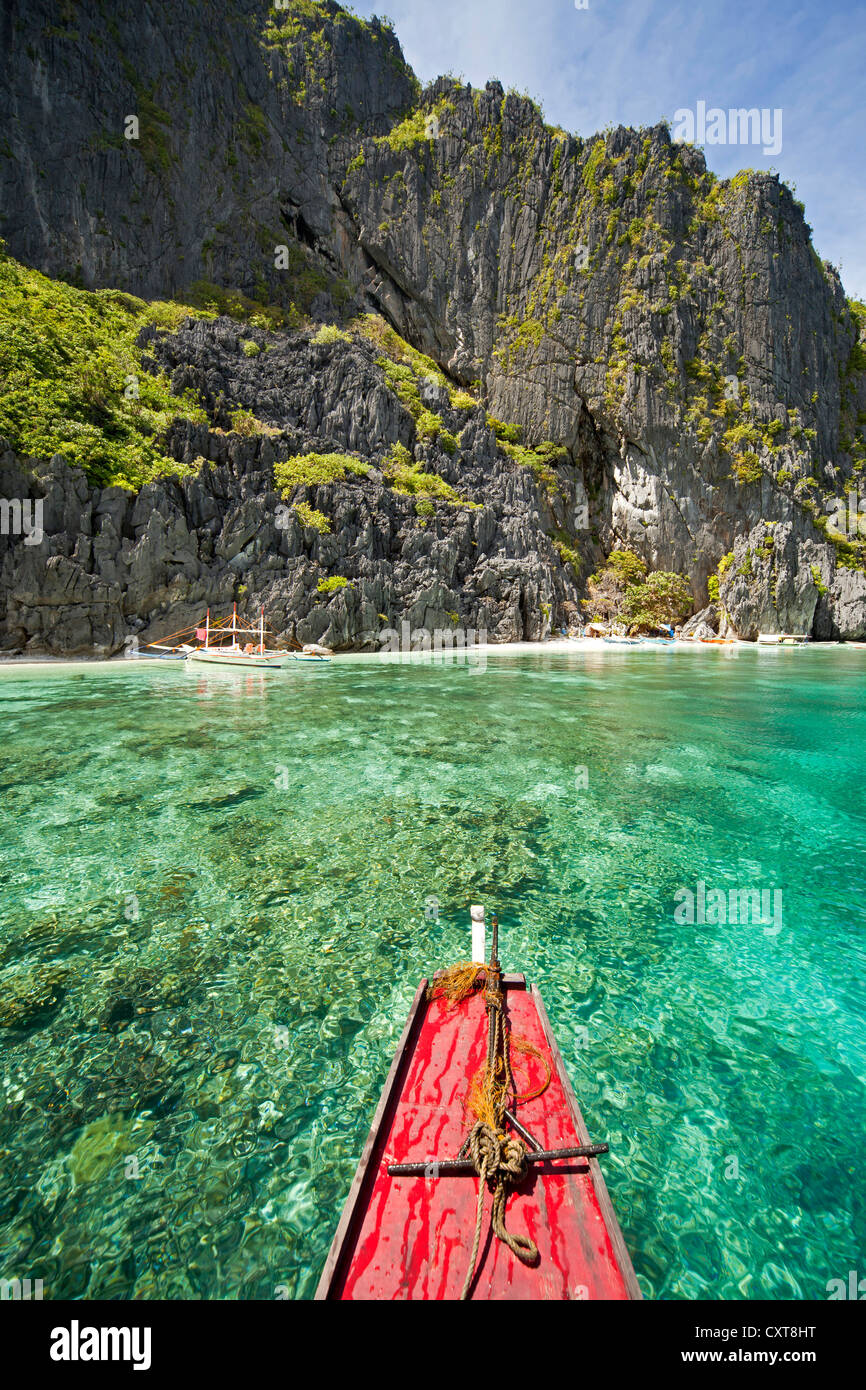 Outrigger boat off the steep limestone coast of Tapiutan Island, Bacuit ...