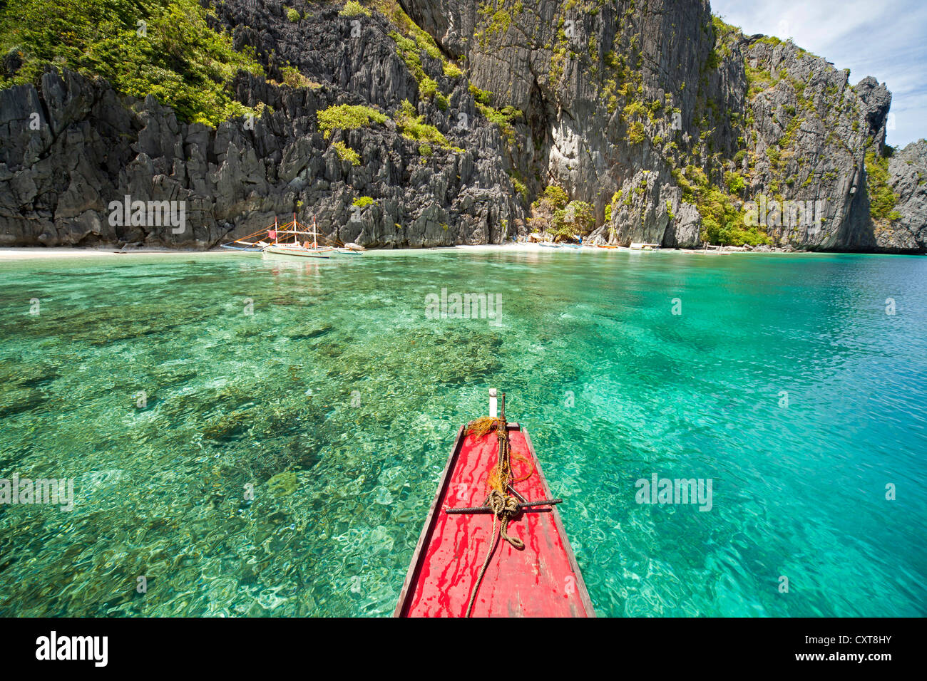 Outrigger boat off the steep limestone coast of Tapiutan Island, Bacuit ...